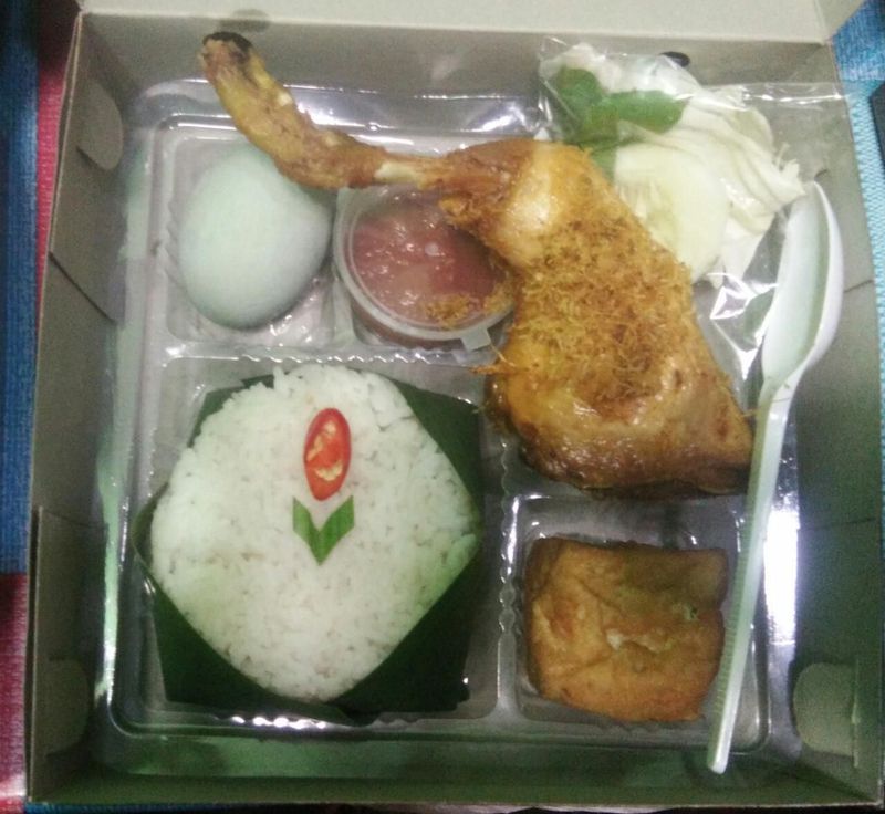 Nasi box berisi nasi, ayam kremes, telor, sambal, kemangi, tahu